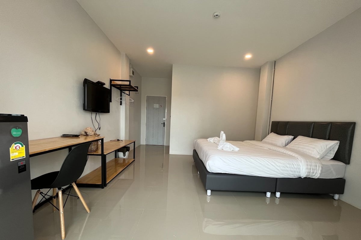 Quarto de hotel moderno com cama, escrivaninha e televisão.