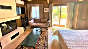 Um quarto aconchegante com lareira, sofá, cama e mesa de jantar.