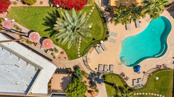 Vista aérea de um resort com piscina, espreguiçadeiras e uma área de varanda coberta.