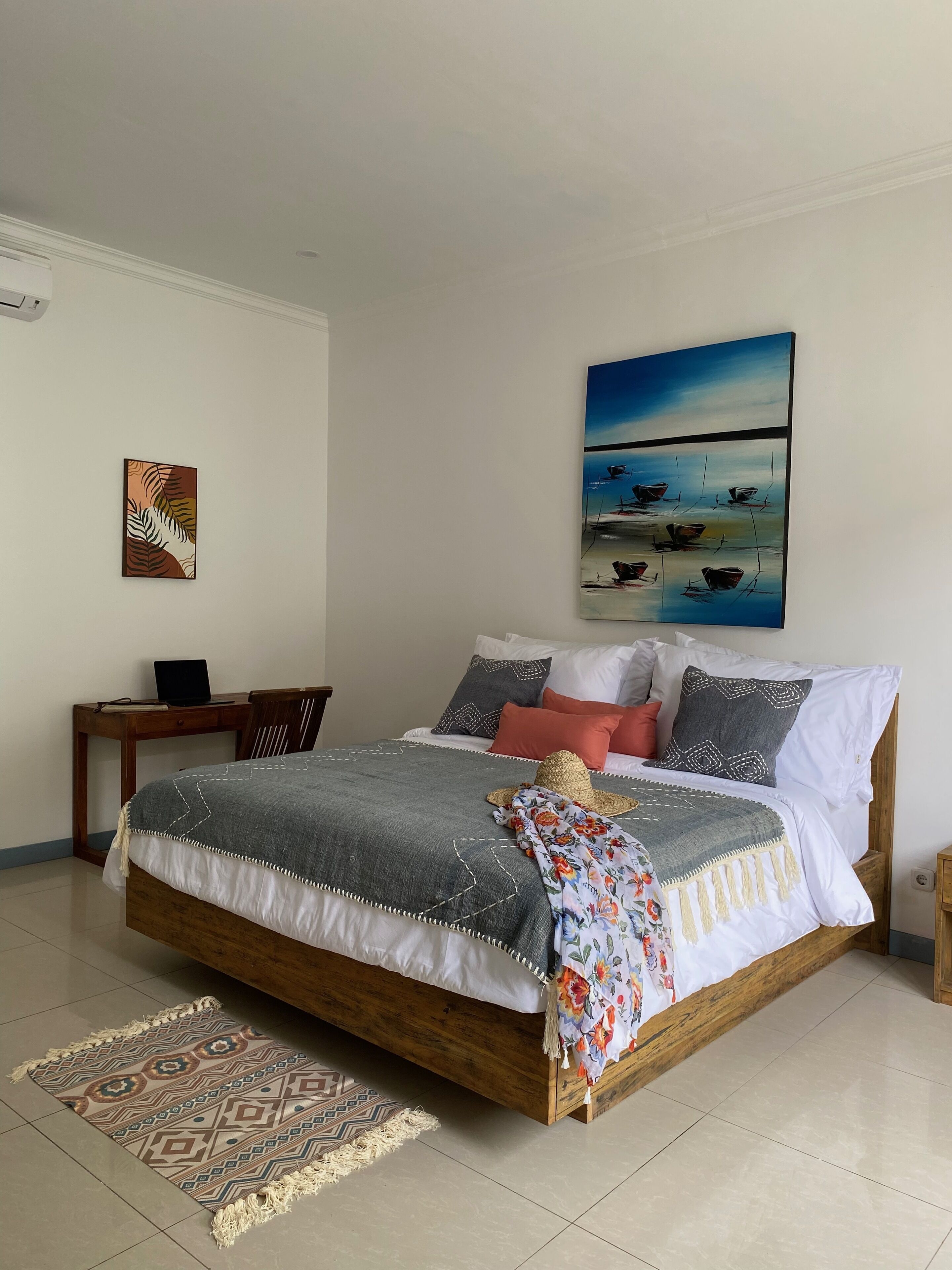 Quarto com cama de madeira, escrivaninha, cadeira e um quadro na parede.