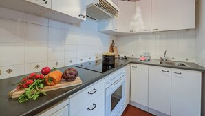 Uma cozinha com armários brancos, bancada preta e fogão.