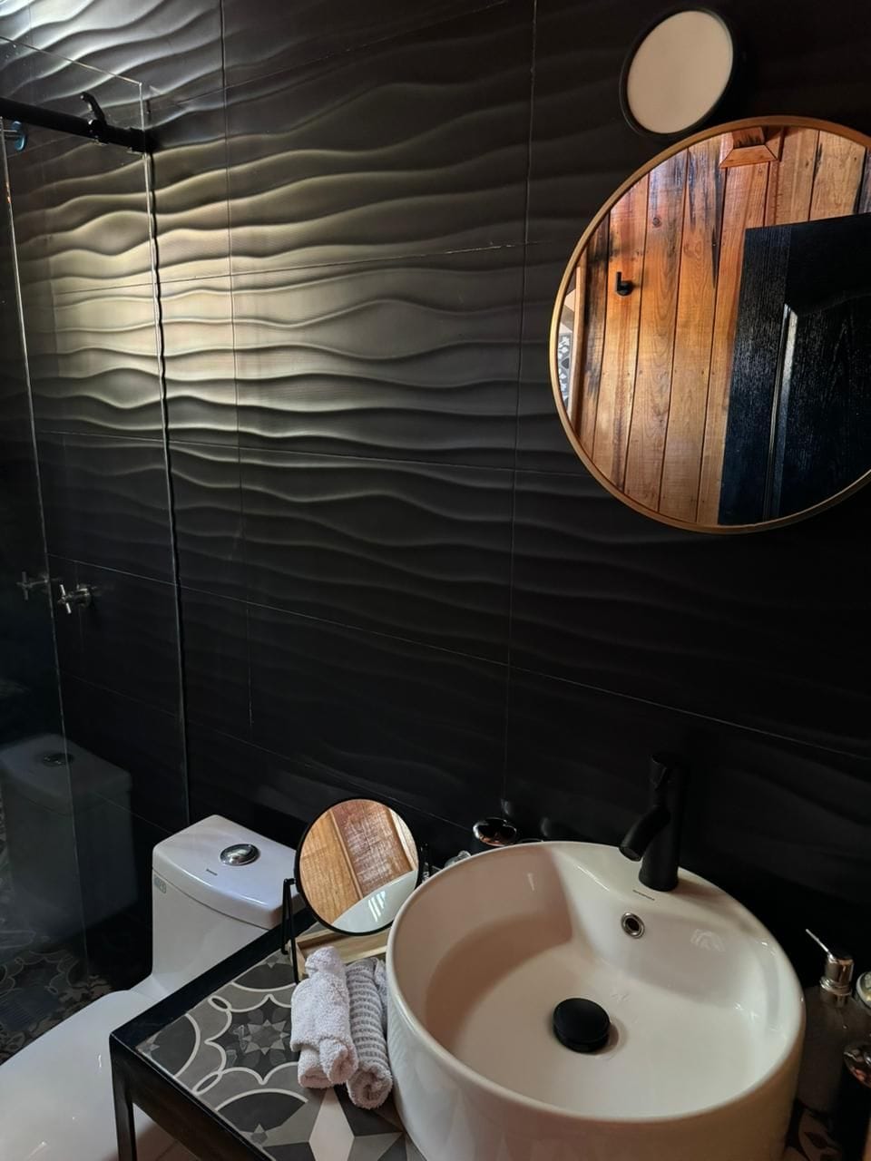 Uma casa de banho moderna com uma grande pia oval, um espelho redondo e uma sanita.