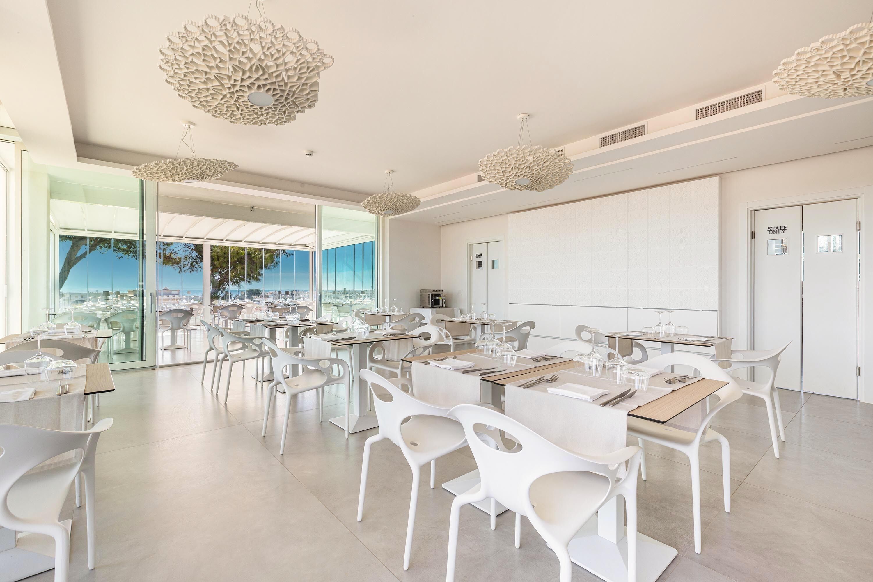 Uma sala de conferências moderna com mobiliário branco, janelas amplas e vista para a cidade.
