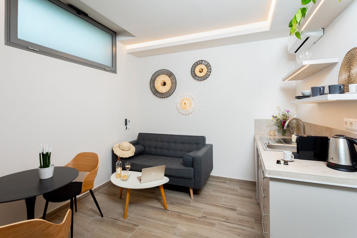 Um espaço compacto para viver, com sofá, mesa de jantar e cozinha compacta.