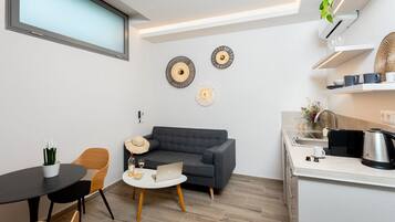 Um espaço compacto para viver, com sofá, mesa de jantar e cozinha compacta.