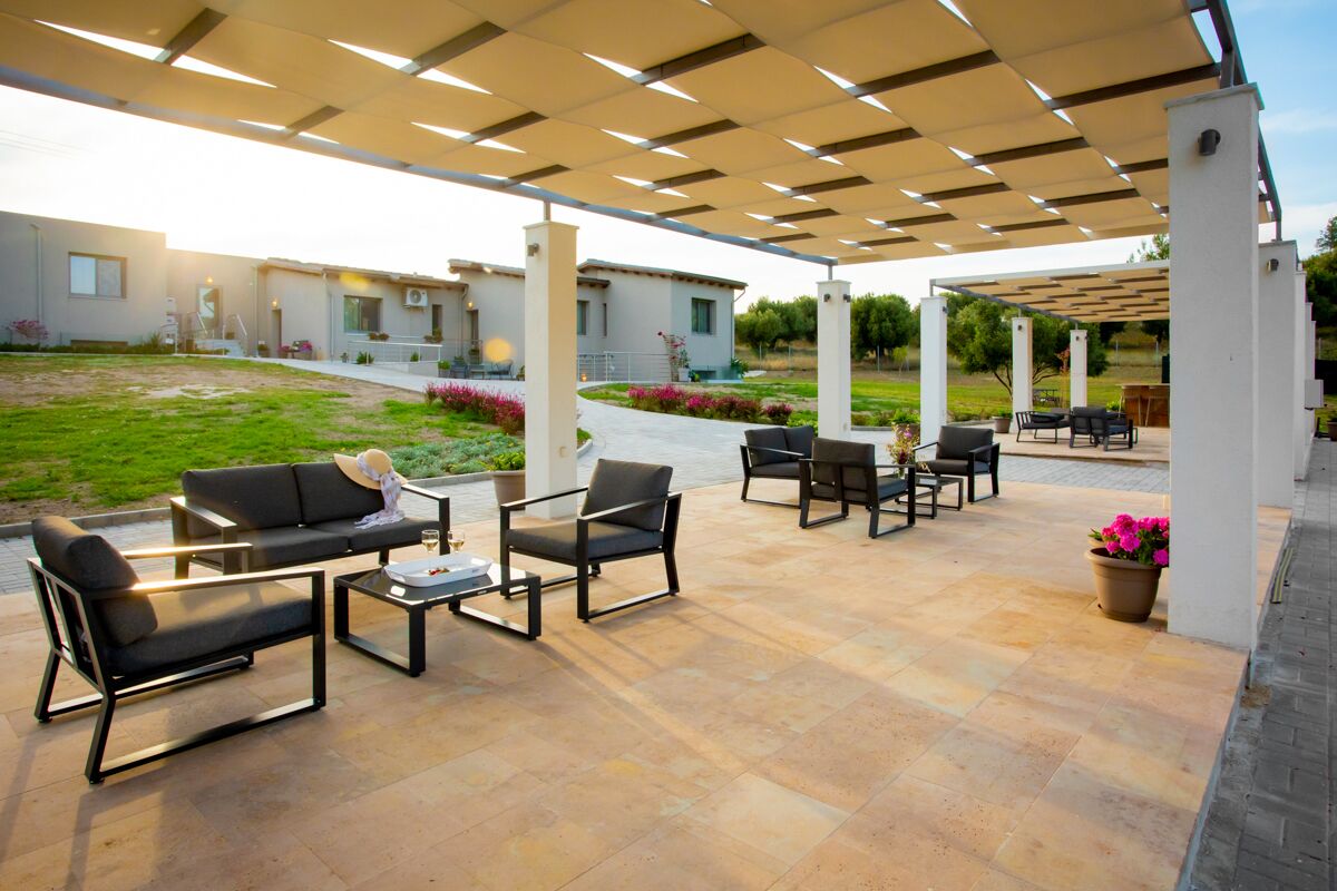 Uma área de pátio externa com móveis modernos, um espaço coberto para sentar e vista para um edifício residencial.