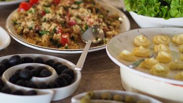 Uma mesa com vários pratos, incluindo azeitonas, salada e um prato com uma colher.