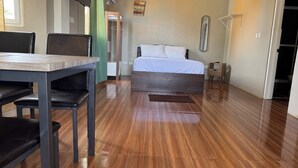 Quarto com cama, mesa, cadeiras, espelho e ar-condicionado fixado na parede.