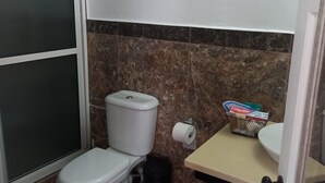 Um banheiro pequeno com vaso sanitário, chuveiro e pia.