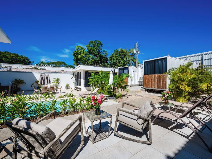 Um terraço no telhado com móveis de exterior, uma piscina e vegetação exuberante.