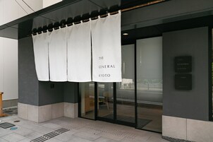A building entrance with a white banner reading "THE GENERAL KYOTO" and a sign indicating "THE GENERAL KYOTO" on the wall.