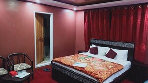 Quarto com cama, duas cadeiras, uma mesinha e uma porta.