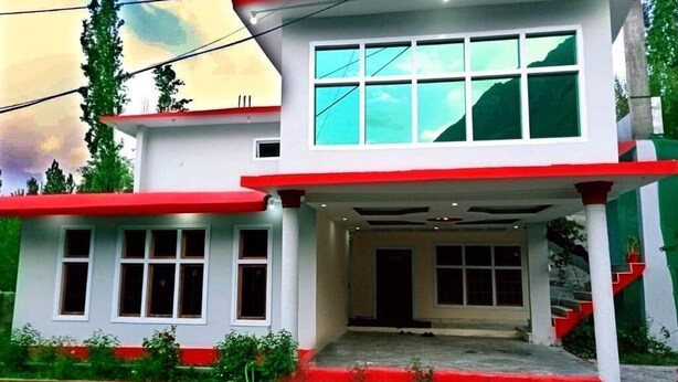 Um edifício de dois andares com telhado plano, grandes janelas e esquema de cores vermelho e branco.