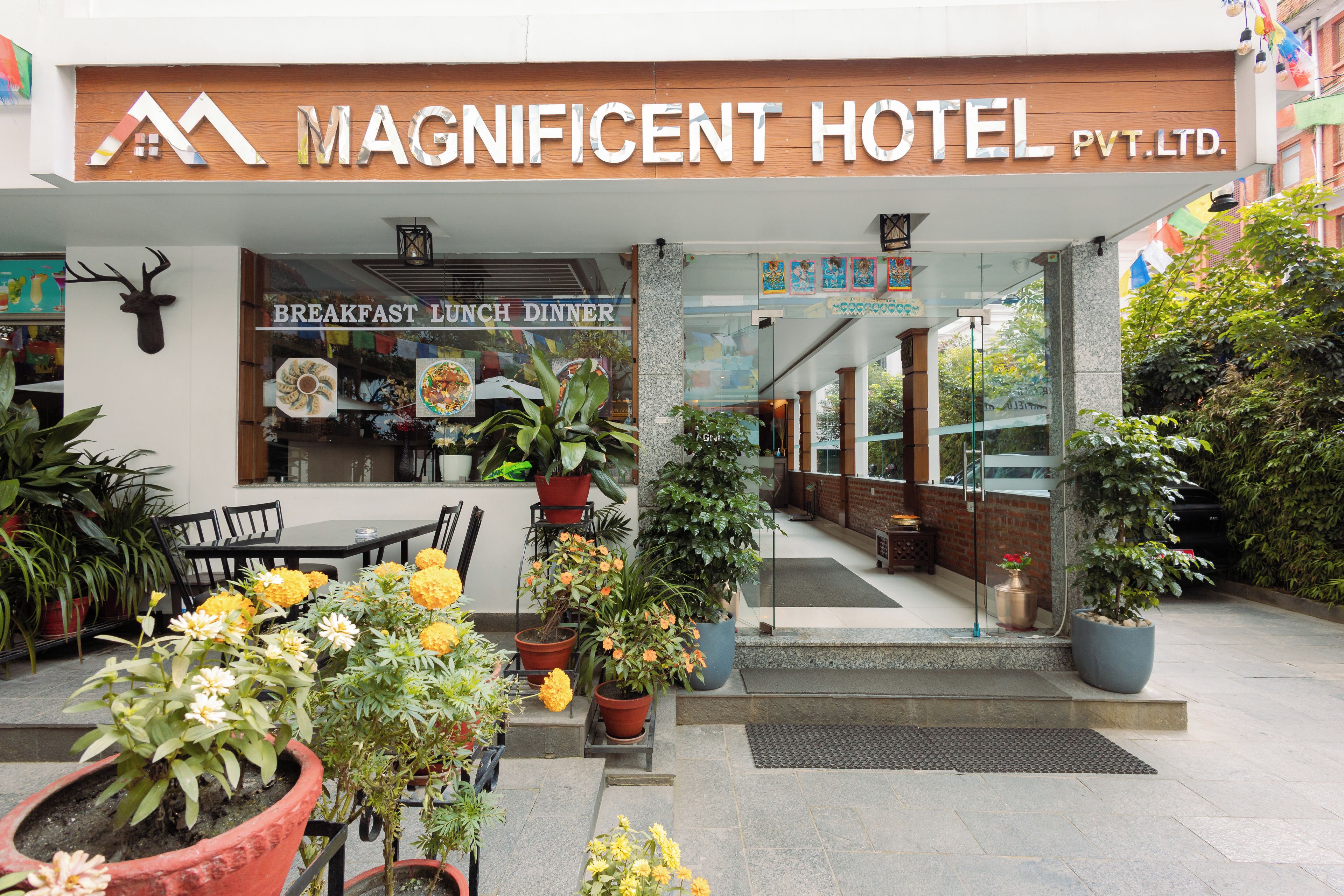 Exterior do Magnífico Hotel, com placa indicando café da manhã, almoço e jantar.