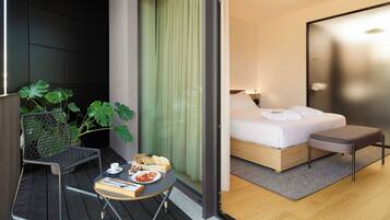 Quarto de hotel moderno com cama, mesa de cabeceira e uma pequena varanda com cadeira e plantas em vasos.
