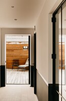 Um corredor moderno com parede de madeira, uma cadeira e uma porta que dá para outro quarto.