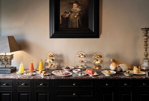 Um buffet de café da manhã com diversos alimentos e um retrato emoldurado acima do balcão.