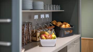 Um balcão de café da manhã com uma tigela de frutas, uma cesta de croissants e potes de granola.