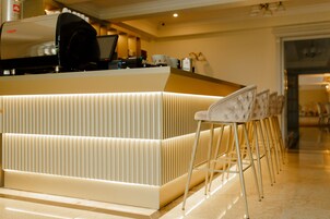 Uma área de bar moderna com balcão, banquetas e uma máquina de café.