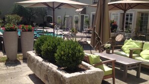 Área de varanda externa com piscina, espaços para sentar e guarda-sóis.