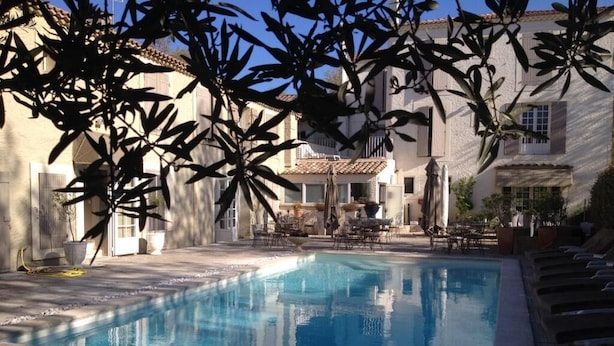 Piscina com espreguiçadeiras, guarda-sóis e plantas em vasos.