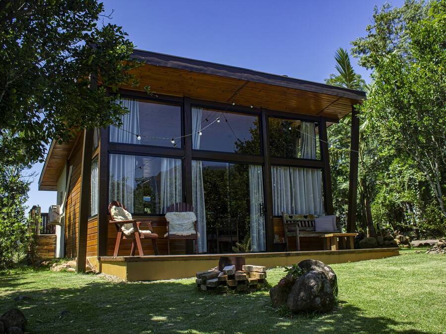 Uma casa moderna com grandes janelas, deck de madeira e gramado.