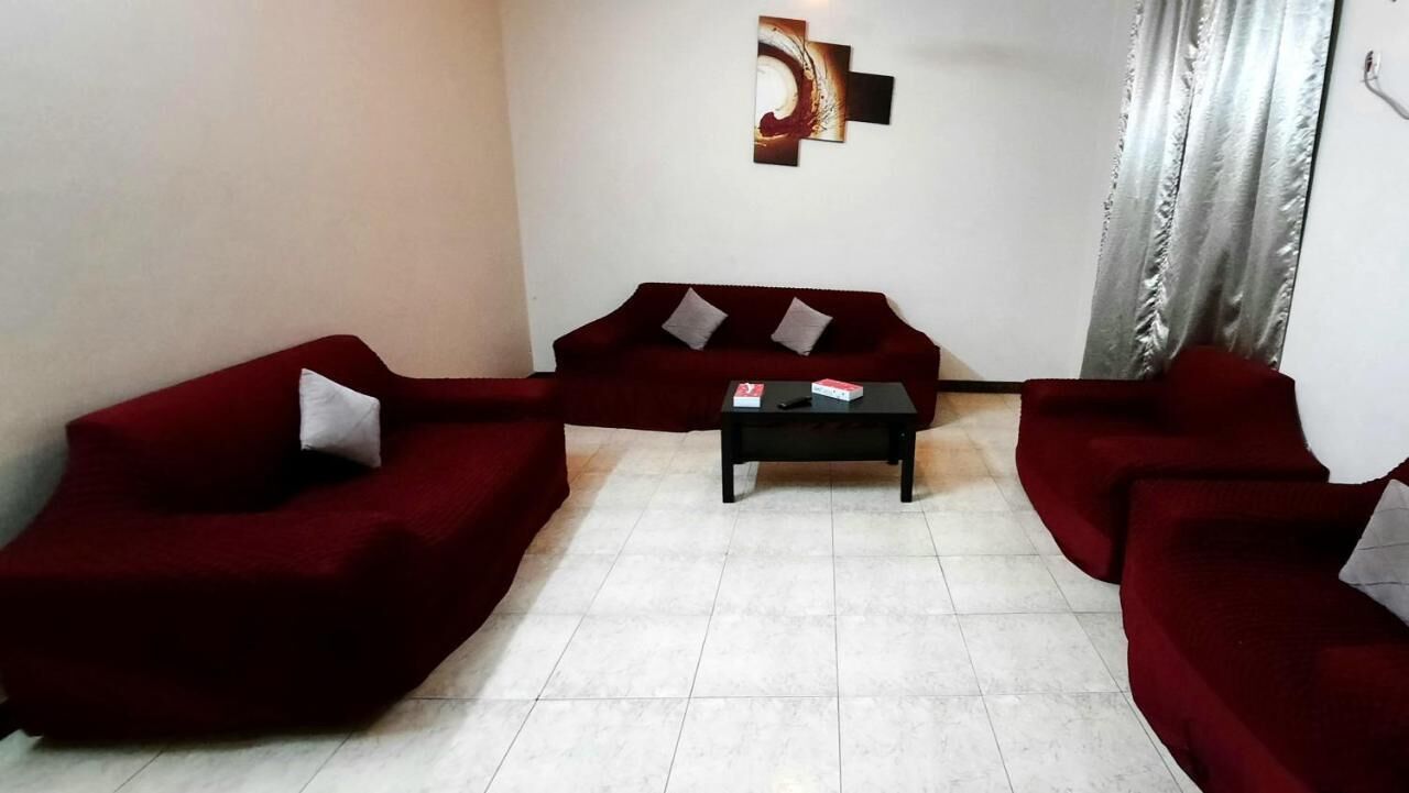 Uma sala de estar com um sofá vermelho, uma mesa de centro e uma obra de arte na parede.