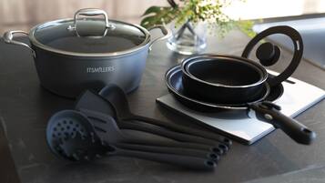 Uma cozinha com uma panela, frigideira e espátulas em uma bancada.