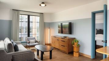 Uma sala de estar moderna com um sofá, uma mesa de centro, uma TV e um armário de madeira.