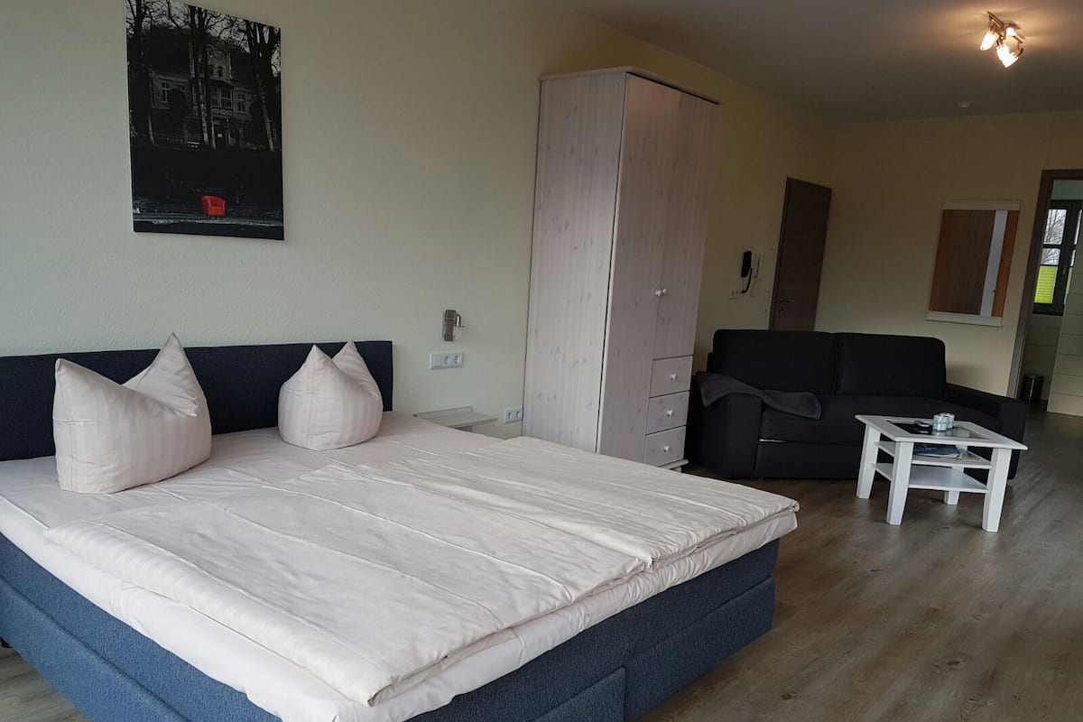 Quarto com uma cama grande, guarda-roupa, sofá e uma pequena mesa.