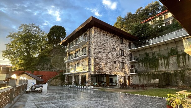 Um edifício moderno com fachada de pedra, área de estar coberta ao ar livre e um pátio pavimentado.