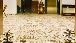 Um hall de hotel com piso de mármore, uma estátua, um balcão de recepção e uma escadaria.