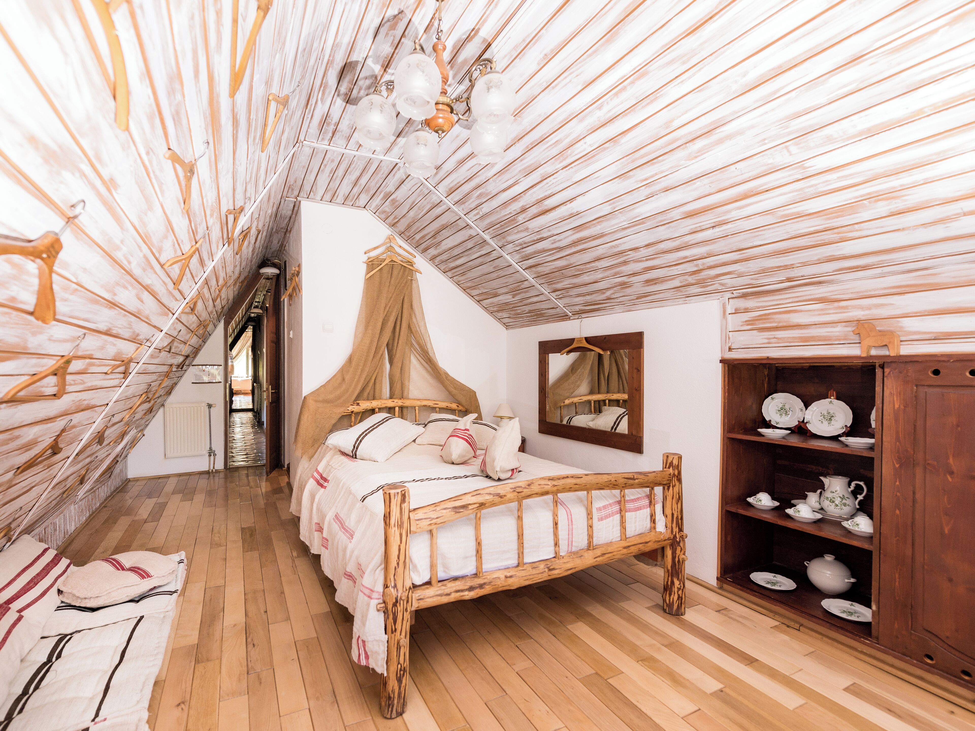 Quarto com cama de madeira, dossel, guarda-roupa de madeira e espelho na parede.