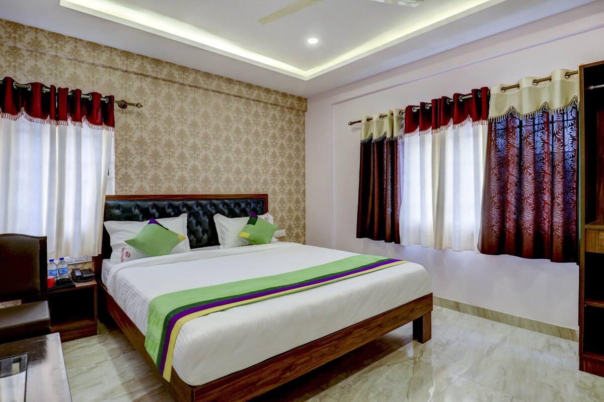 Quarto de hotel com cama, mesa de cabeceira e telefone.