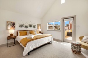 Quarto com uma cama grande, mesa de cabeceira, janela e vista para o exterior.