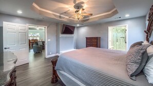Quarto com uma cama grande, um ventilador de teto e vista para a sala de estar.