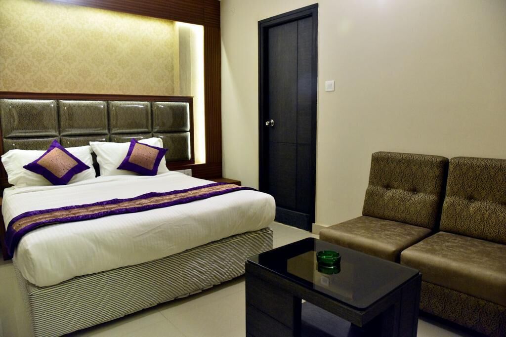 Quarto de hotel com uma cama grande, uma porta escura e um sofá.