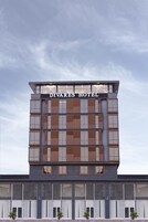 Um edifício moderno de hotel com uma placa chamativa que diz 'DIVARES HOTEL'.