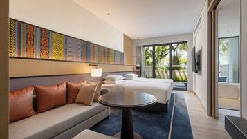 Quarto de hotel moderno com sofá, duas camas, uma mesinha e um ornamento de parede colorido.