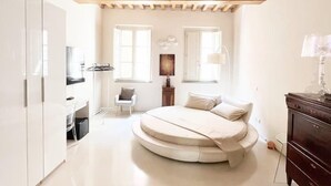 Quarto com cama redonda, escrivaninha, cadeira e guarda-roupa.