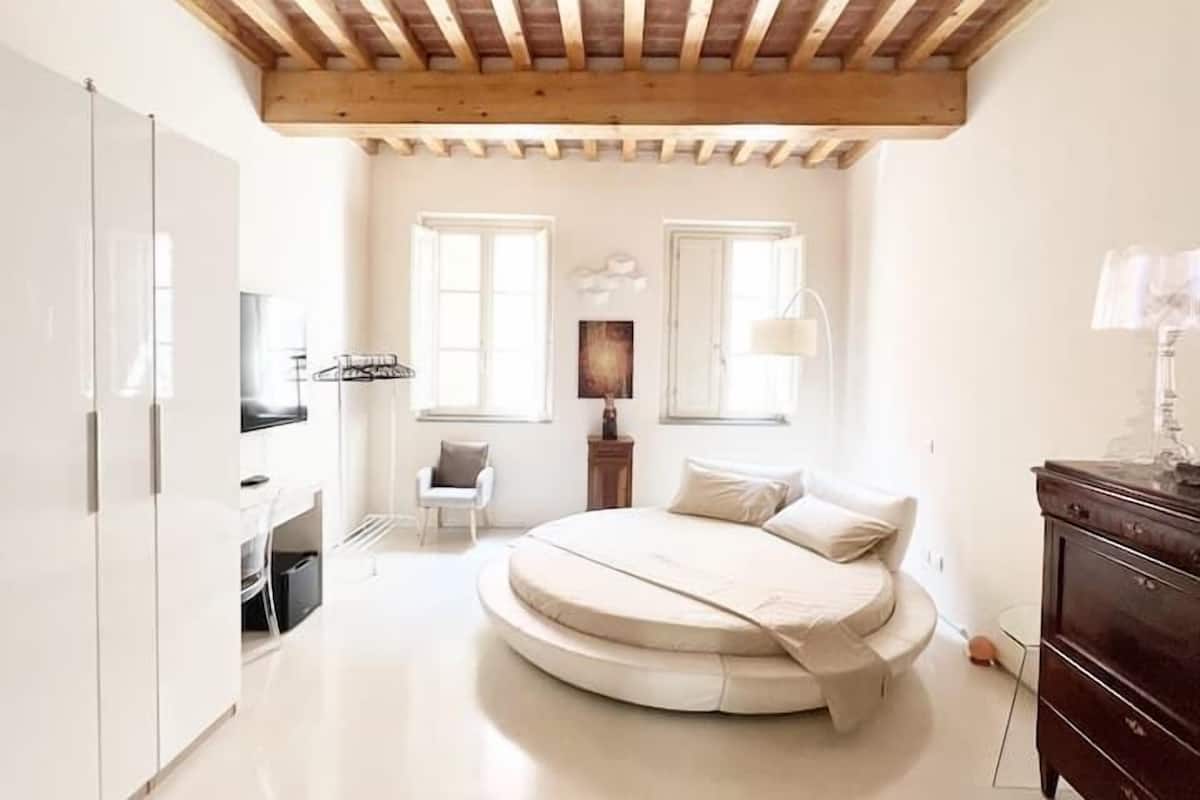 Quarto com cama redonda, escrivaninha, cadeira e guarda-roupa.