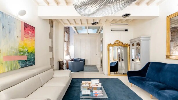 Uma sala de estar moderna com um sofá branco, um sofá azul e uma mesa de centro com revistas.