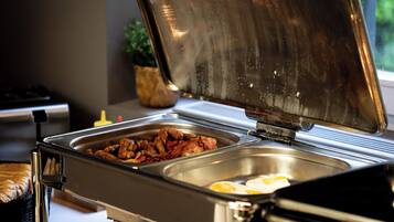 Buffet com diversos alimentos e uma planta ao fundo.