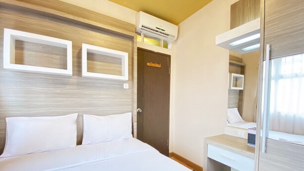 Quarto de hotel com cama grande, mesa de cabeceira, espelho e aparelho de ar condicionado.