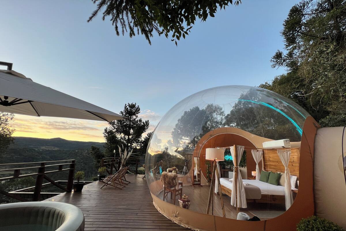 Uma cúpula transparente com uma cama e um deck de madeira.