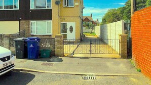 Uma casa residencial com uma entrada por portão, painéis solares no telhado e um carro branco estacionado na frente.