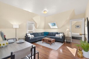 Uma sala de estar moderna com um sofá seccional, uma mesa de centro e uma área de jantar com mesa e cadeiras.