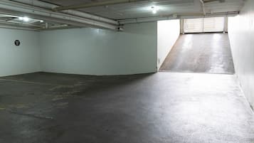 Uma garagem com piso de concreto, teto inclinado e uma janela na parede direita.