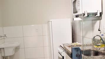 Cozinha com armários brancos, micro-ondas, pia e fogão.