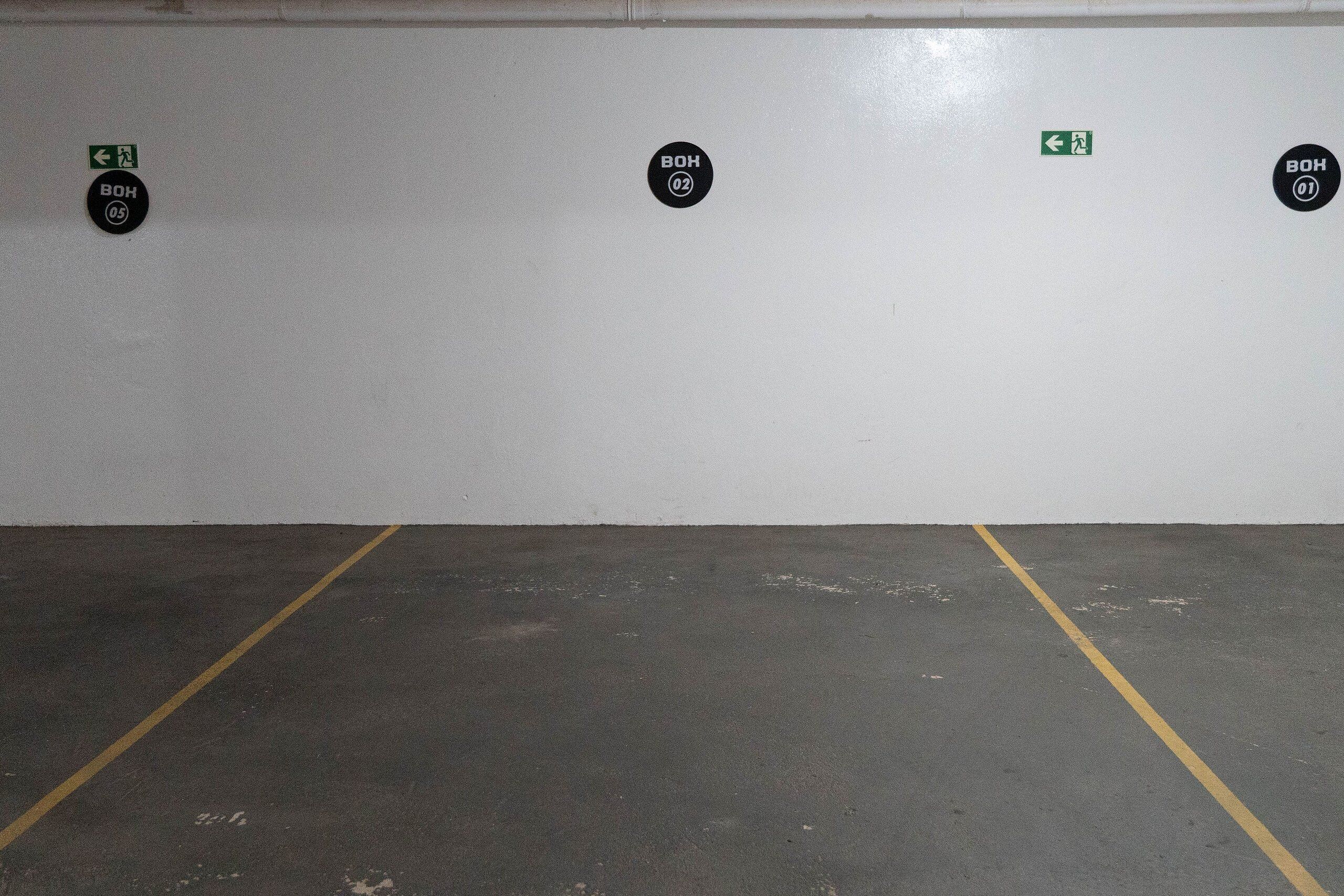 Uma garagem de estacionamento com vagas demarcadas e placas de sinalização.
